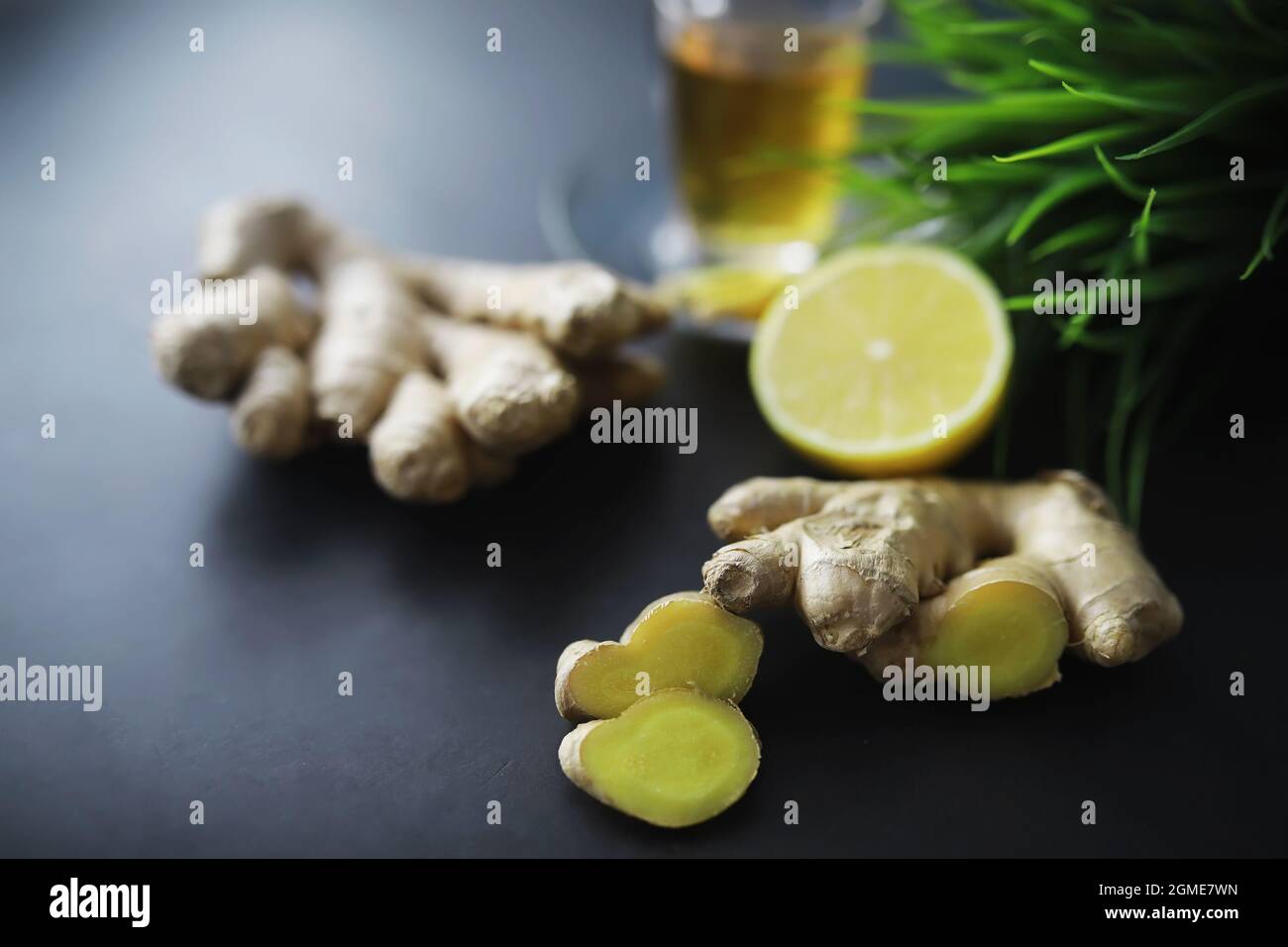 Ginger root whole and sliced. Ginger tea with lemon on the dark ...