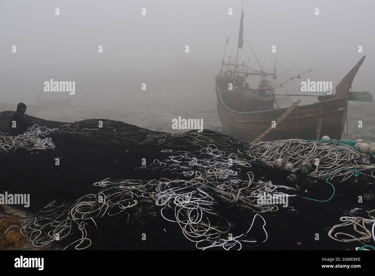 A fisherman fixes his fishing net on a winter's morning Stock Photo - Alamy