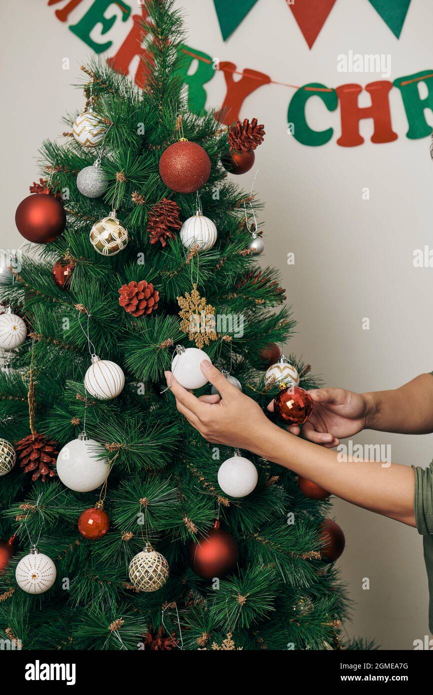handsome man decorating christmas tree with baubles and looking at ...
