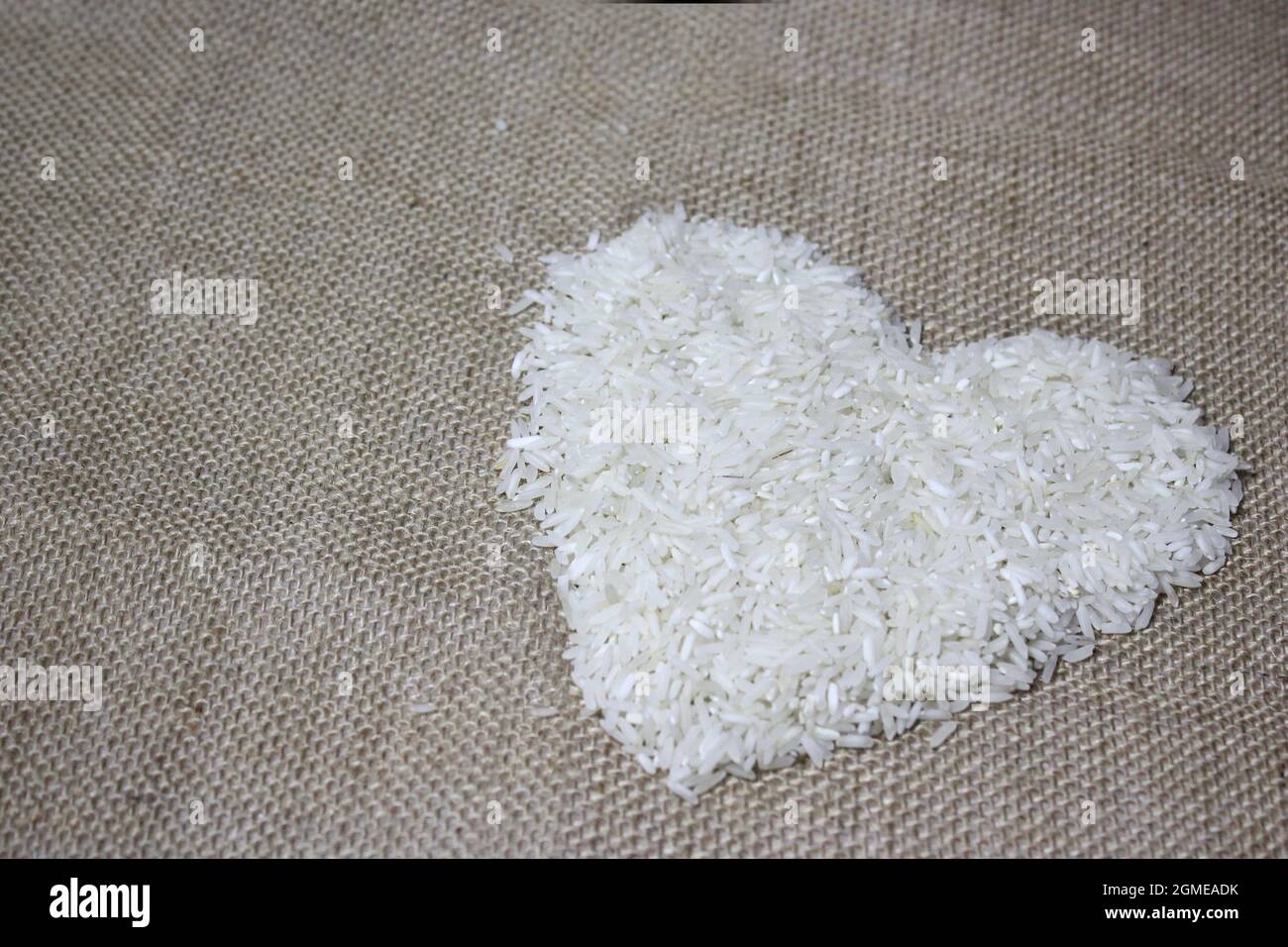 Heart shaped white rice on burlap jute fabric. Selective focus Stock ...