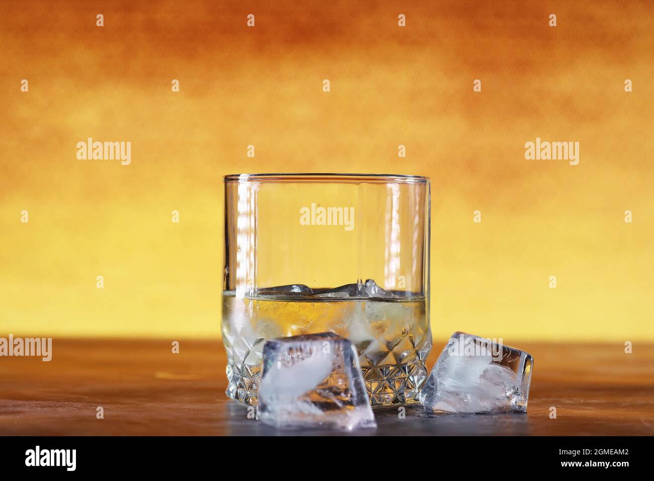 A glass of hard alcohol with ice on a bar counter. Whiskey with soda in ...