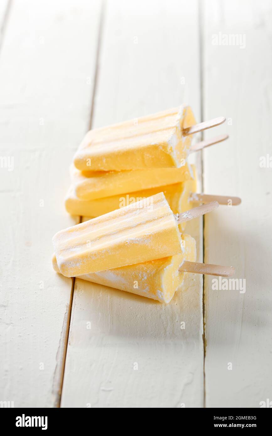 Tall stack of yellow pineapple ice lollies, on a wooden table with ...