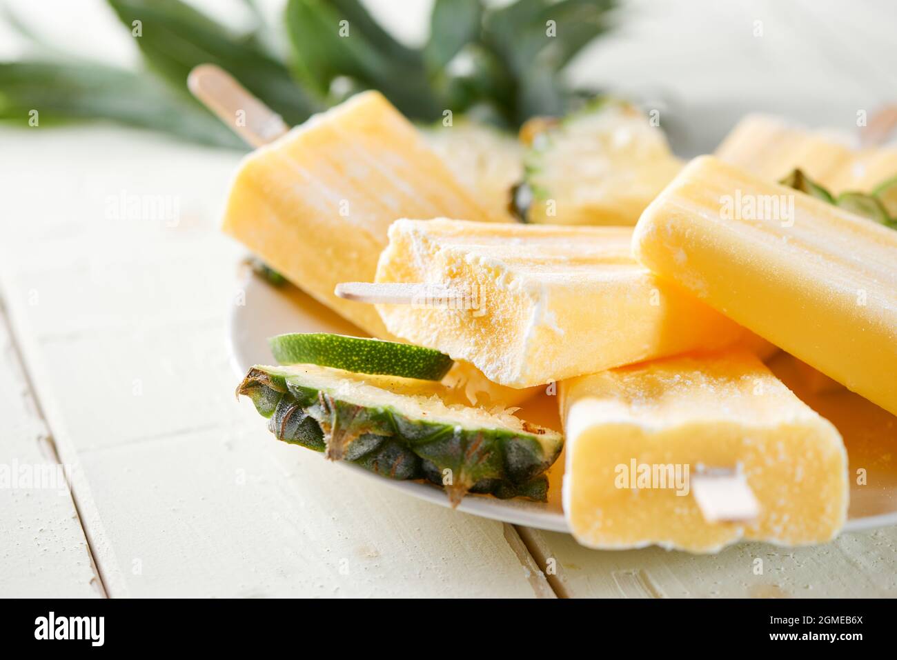 Yellow fruit popsicles on a plate. Top view over a white wood ...