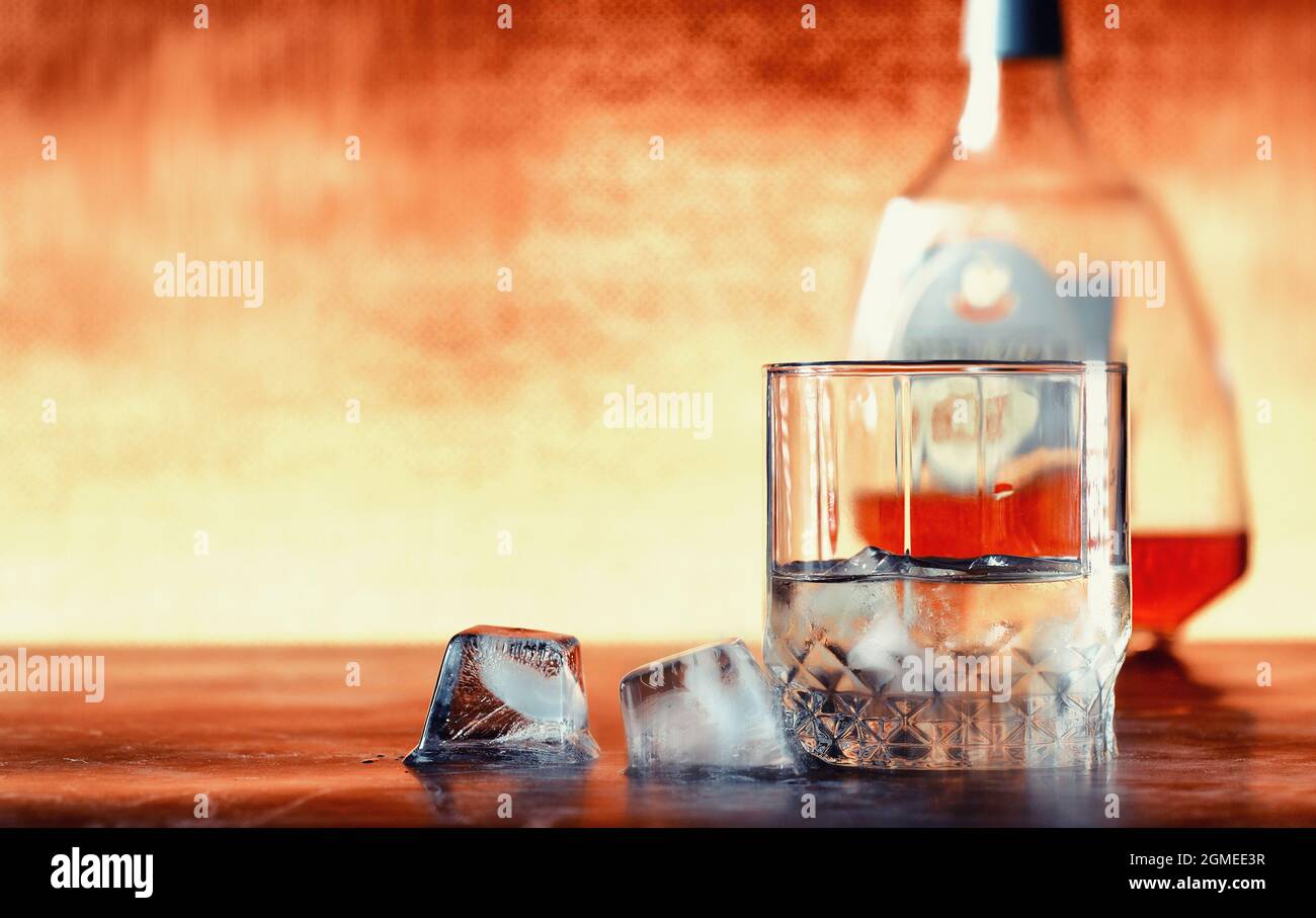 A glass of hard alcohol with ice on a bar counter. Whiskey with soda in ...