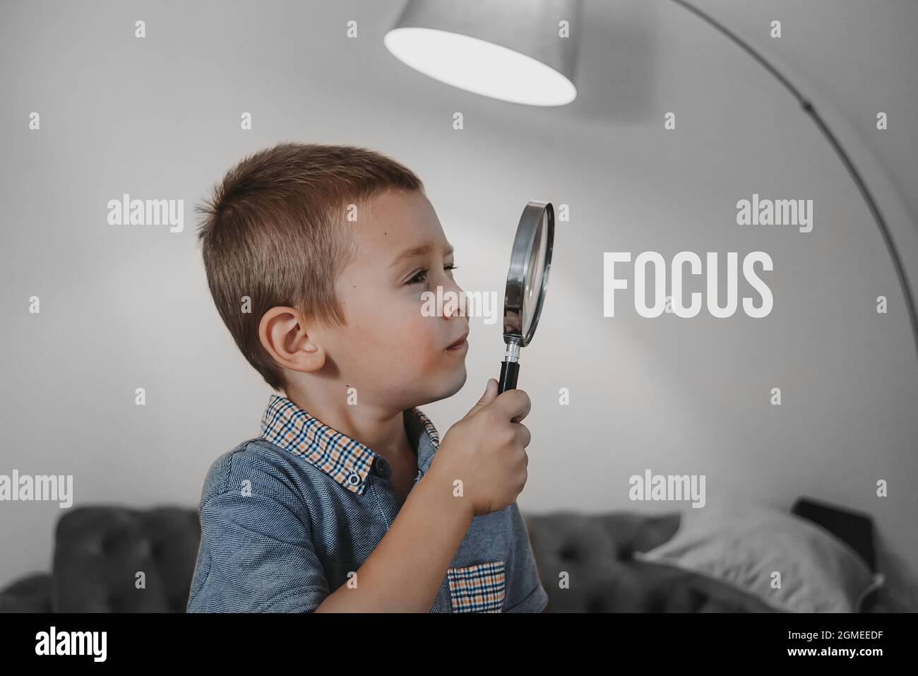 Child holding a magnifying glass with text focus Stock Photo - Alamy