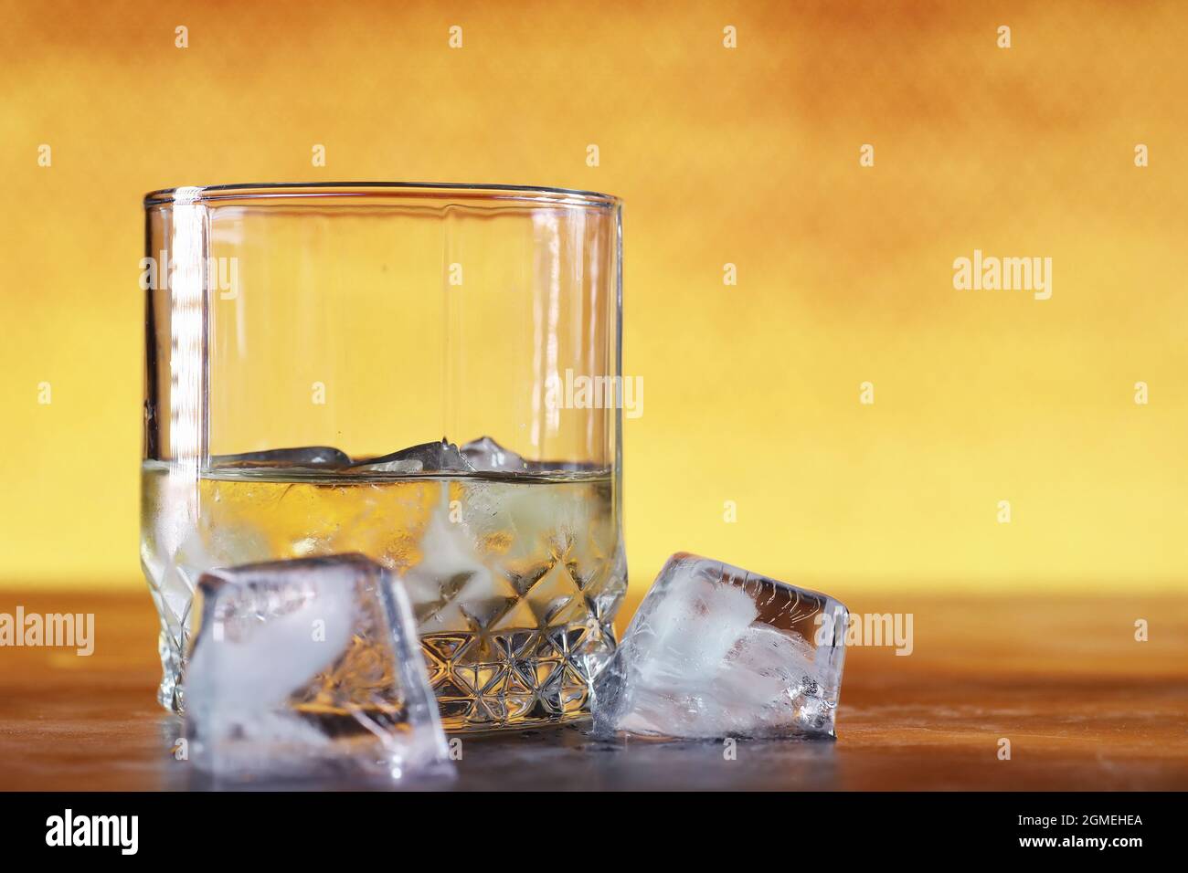 A glass of hard alcohol with ice on a bar counter. Whiskey with soda in ...