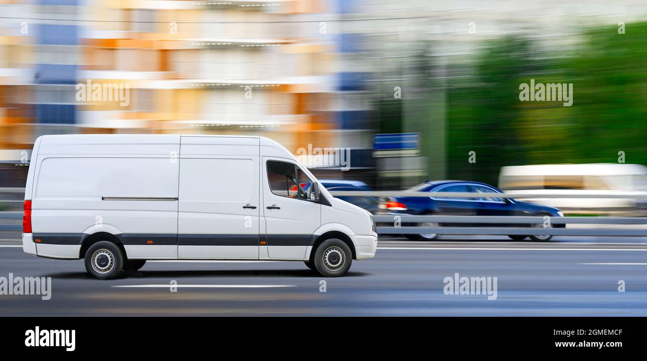 White van drives on city traffic on cityscape background Stock Photo ...
