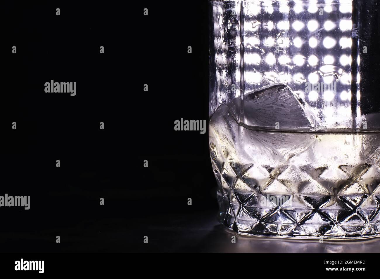 A glass of hard alcohol with ice on a bar counter. Whiskey with soda in ...