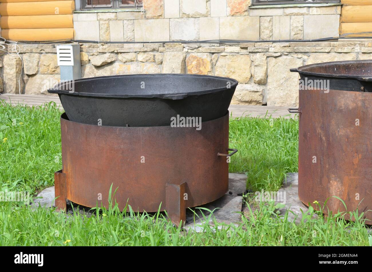 two large black metal cast-iron cauldrons for pilaf on a homemade stand ...