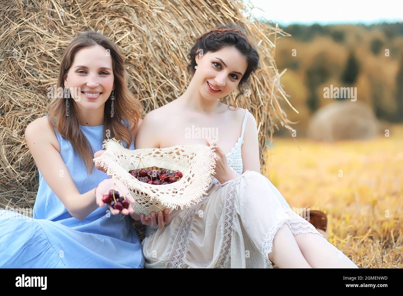 Two beautiful girls in dresses in autumn field with berries Stock Photo ...