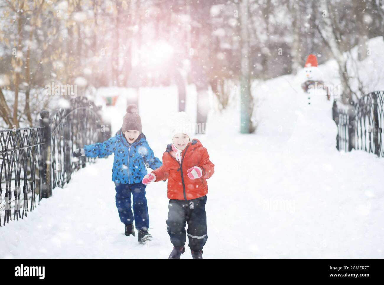 Children in the park in winter. Kids play with snow on the playground ...