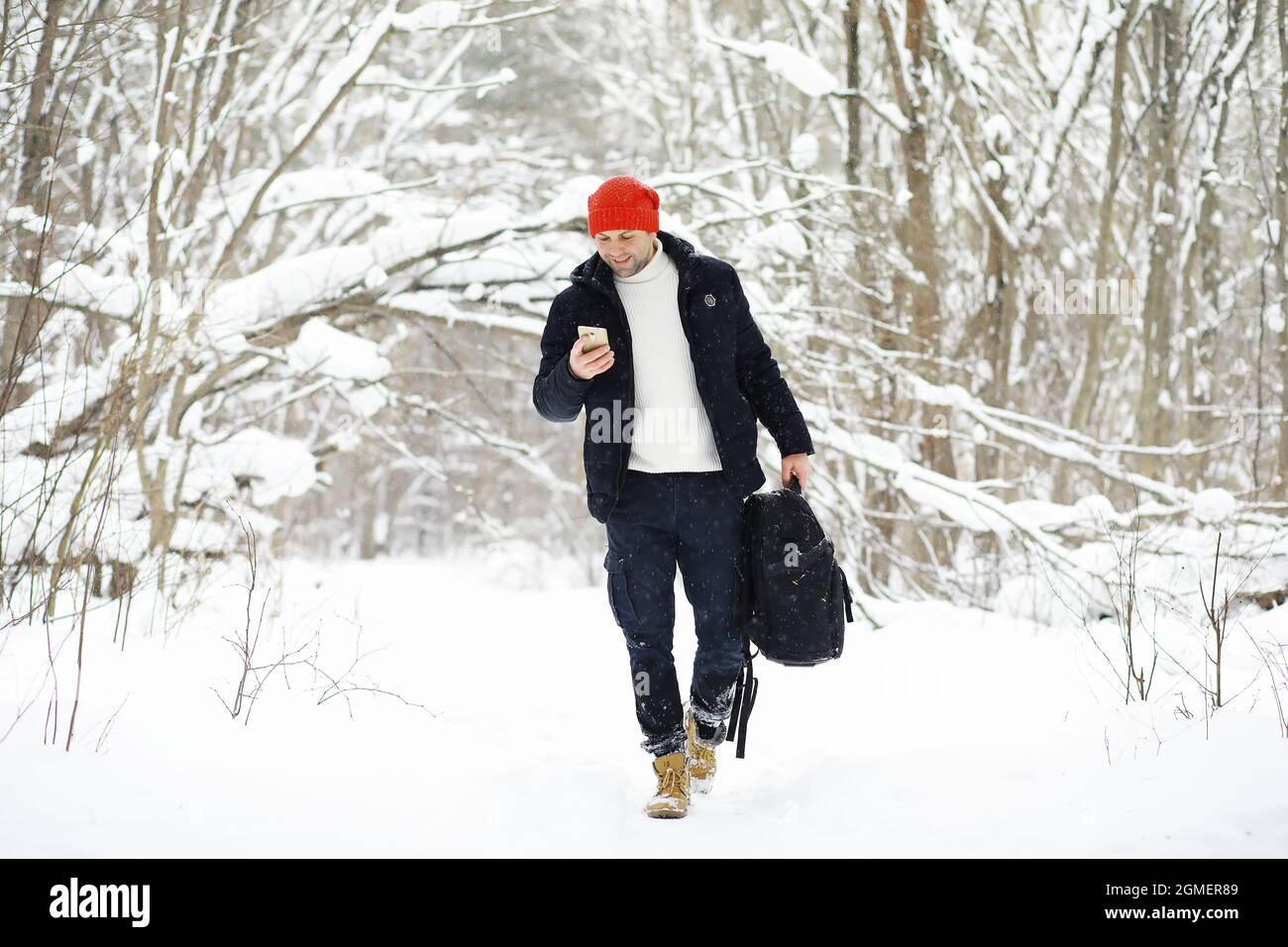 A man in the winter in the forest. A tourist with a backpack goes ...