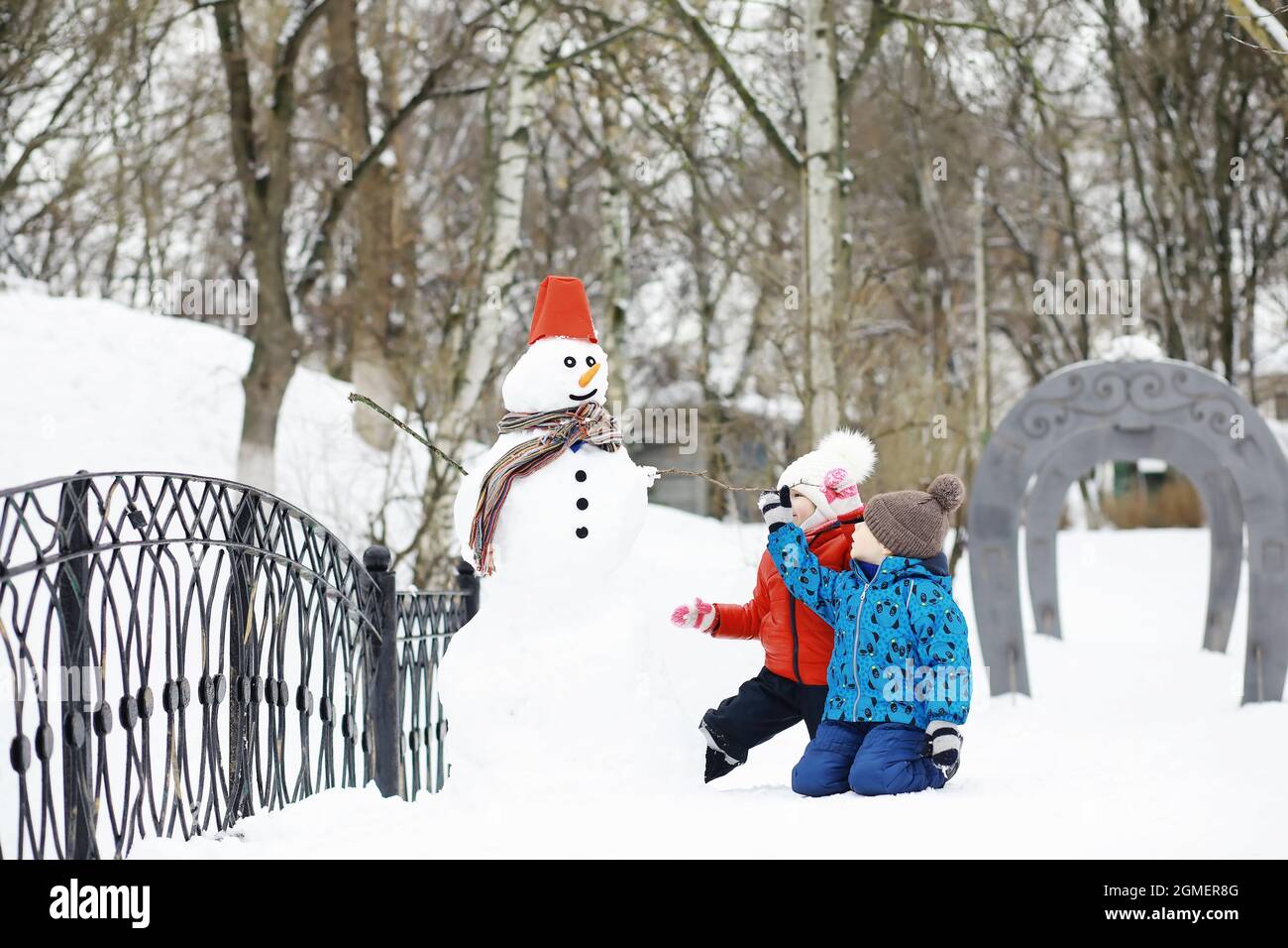 Children in the park in winter. Kids play with snow on the playground ...
