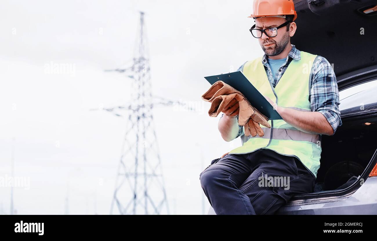 A man in a helmet and uniform, an electrician in the field ...