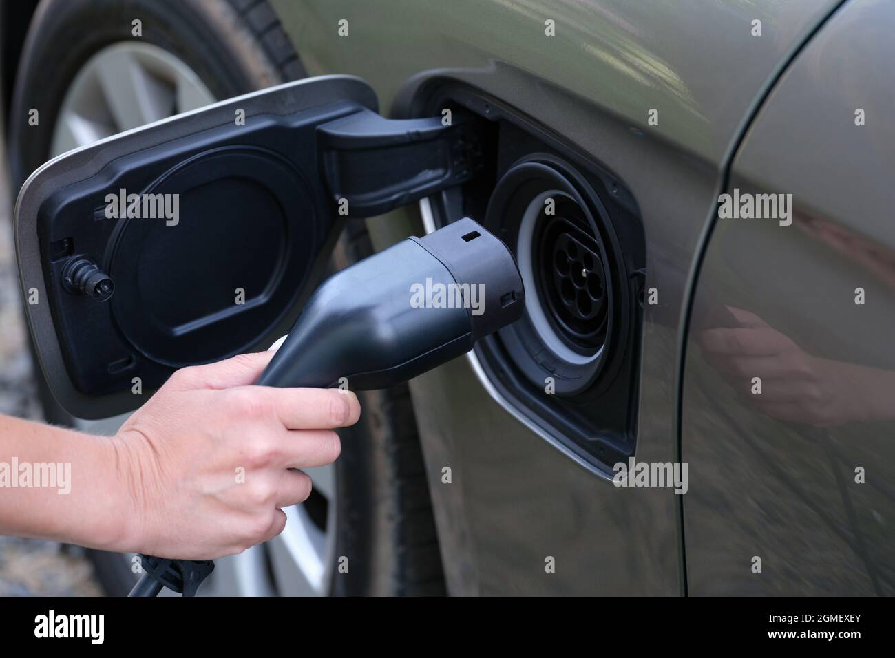 Man inserting electric cable into car charger closeup. Environmentally ...