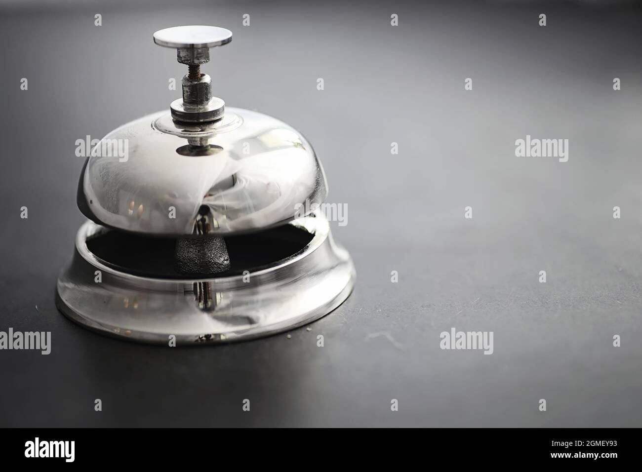 A shiny silver metal bell at hotel reception. A table in the hotel at ...