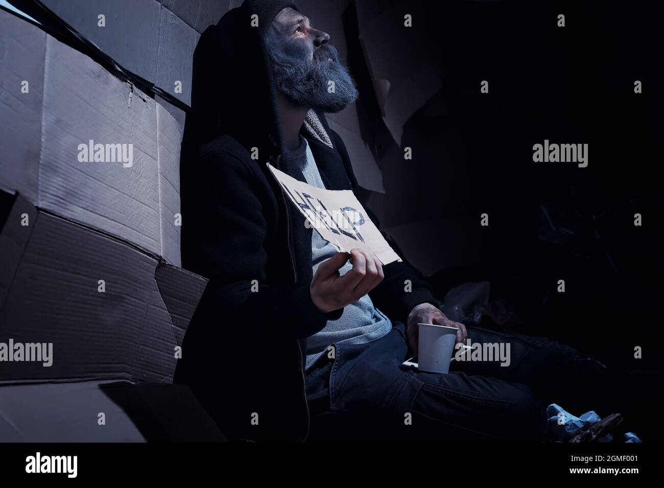 A homeless bearded man sits on boxes on street and asks for help. Need ...