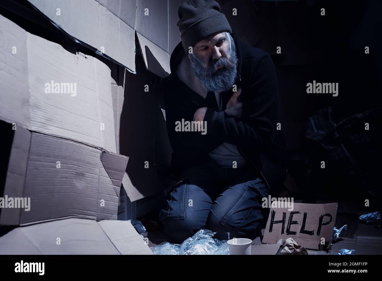 A homeless bearded man sits on boxes on street and asks for help. Need ...