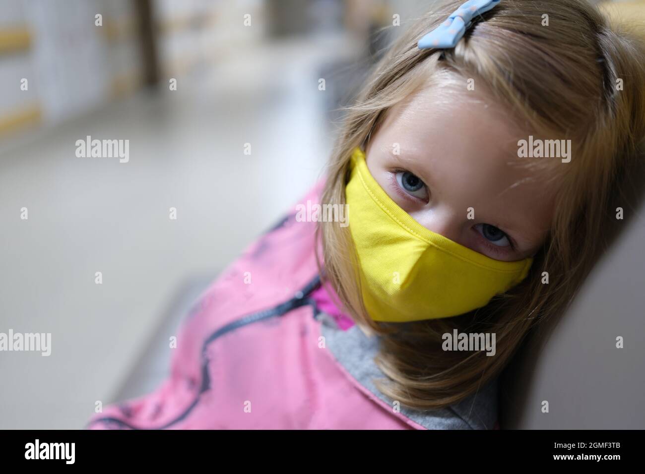 Little girl in yellow protective medical mask sitting in hospital ...