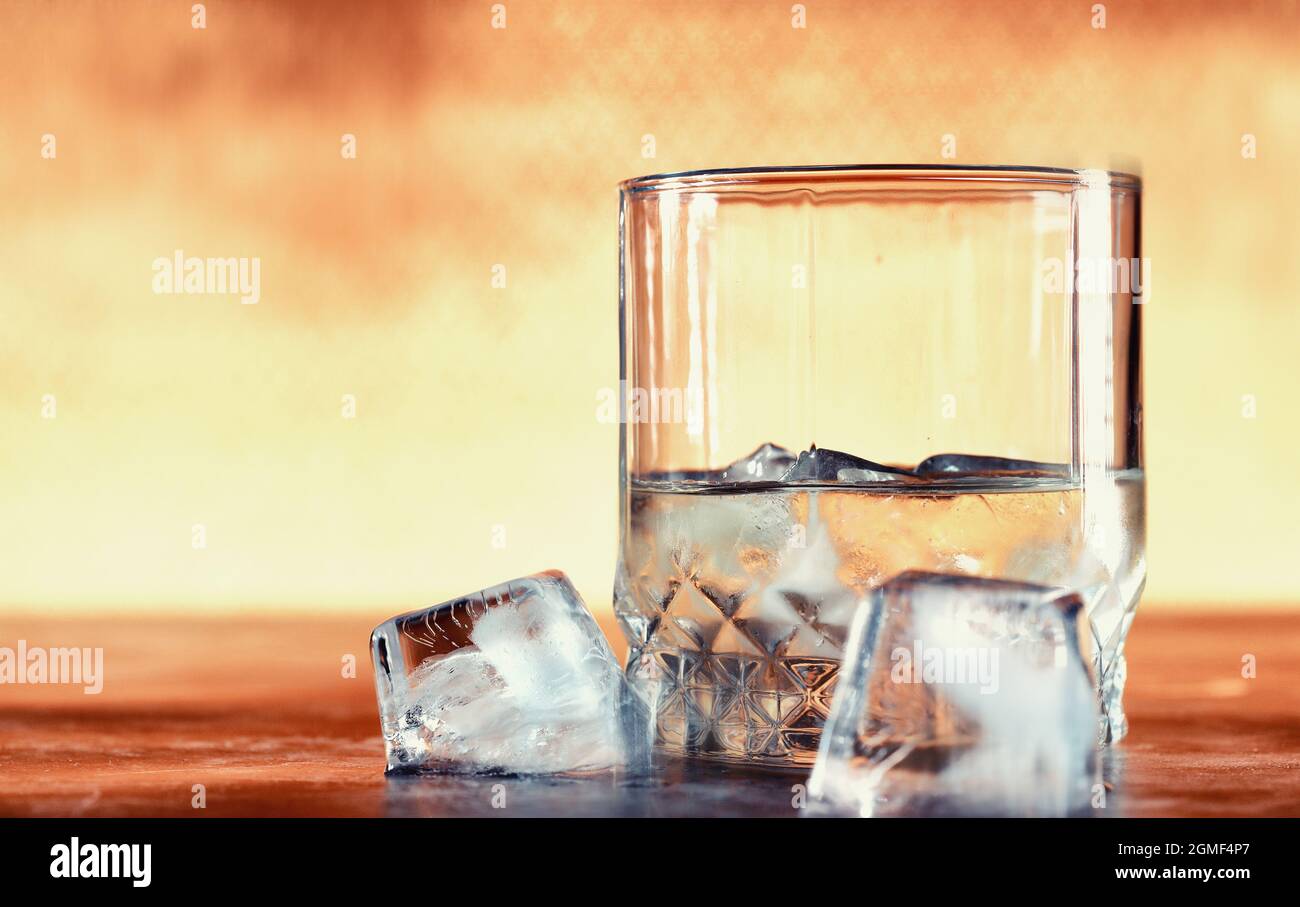 A glass of hard alcohol with ice on a bar counter. Whiskey with soda in ...
