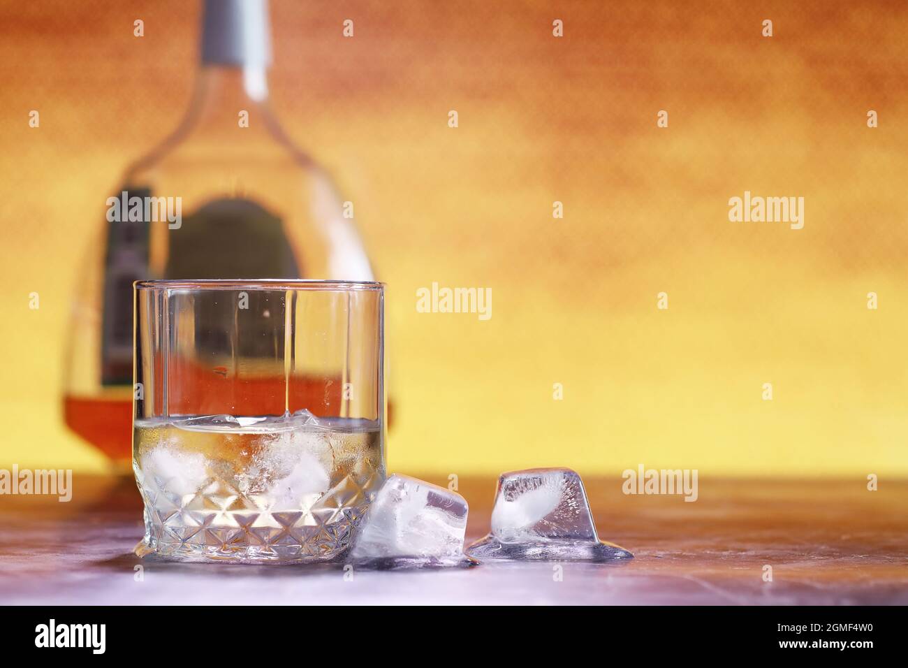 A glass of hard alcohol with ice on a bar counter. Whiskey with soda in ...
