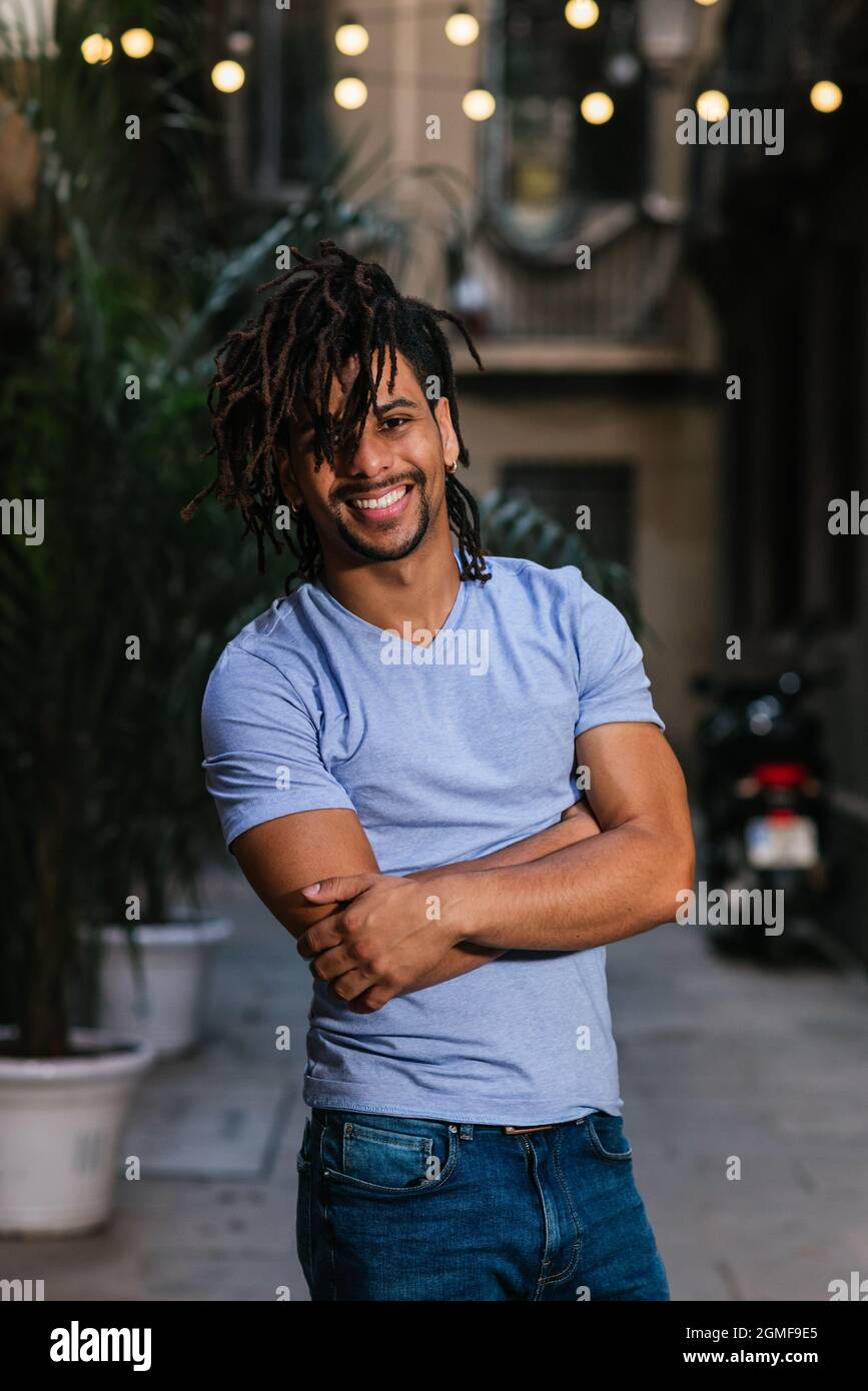 vertical portrait of an hispanic young man with dreadlocks. He is ...