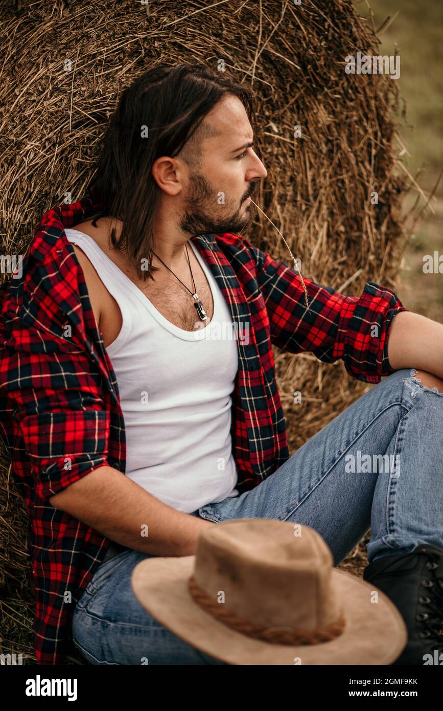 Young handsome Serbian male in a flannel shirt and ripped jeans sitting ...