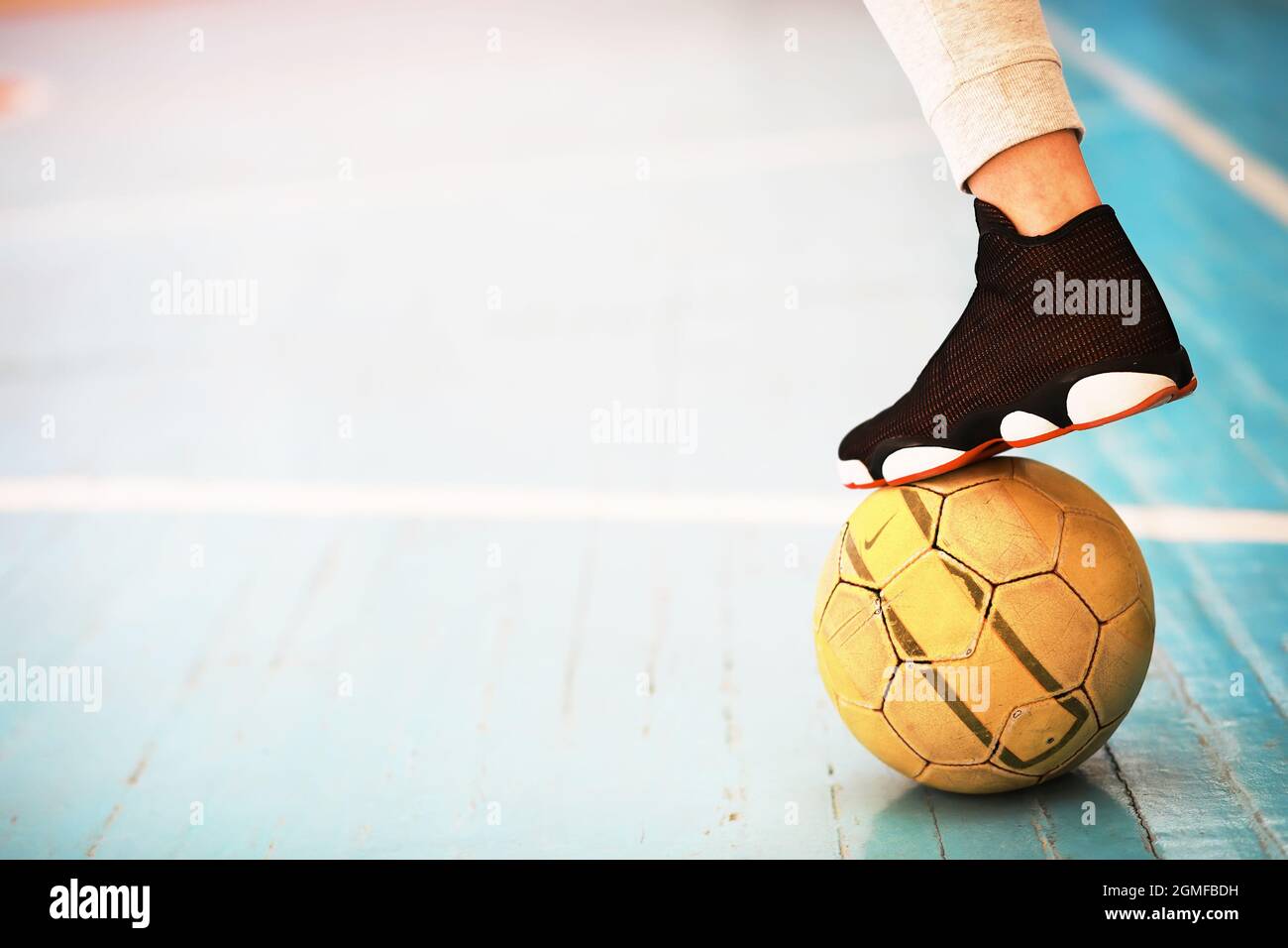 A human foot rest on the football on concrete floor. Photo of one ...
