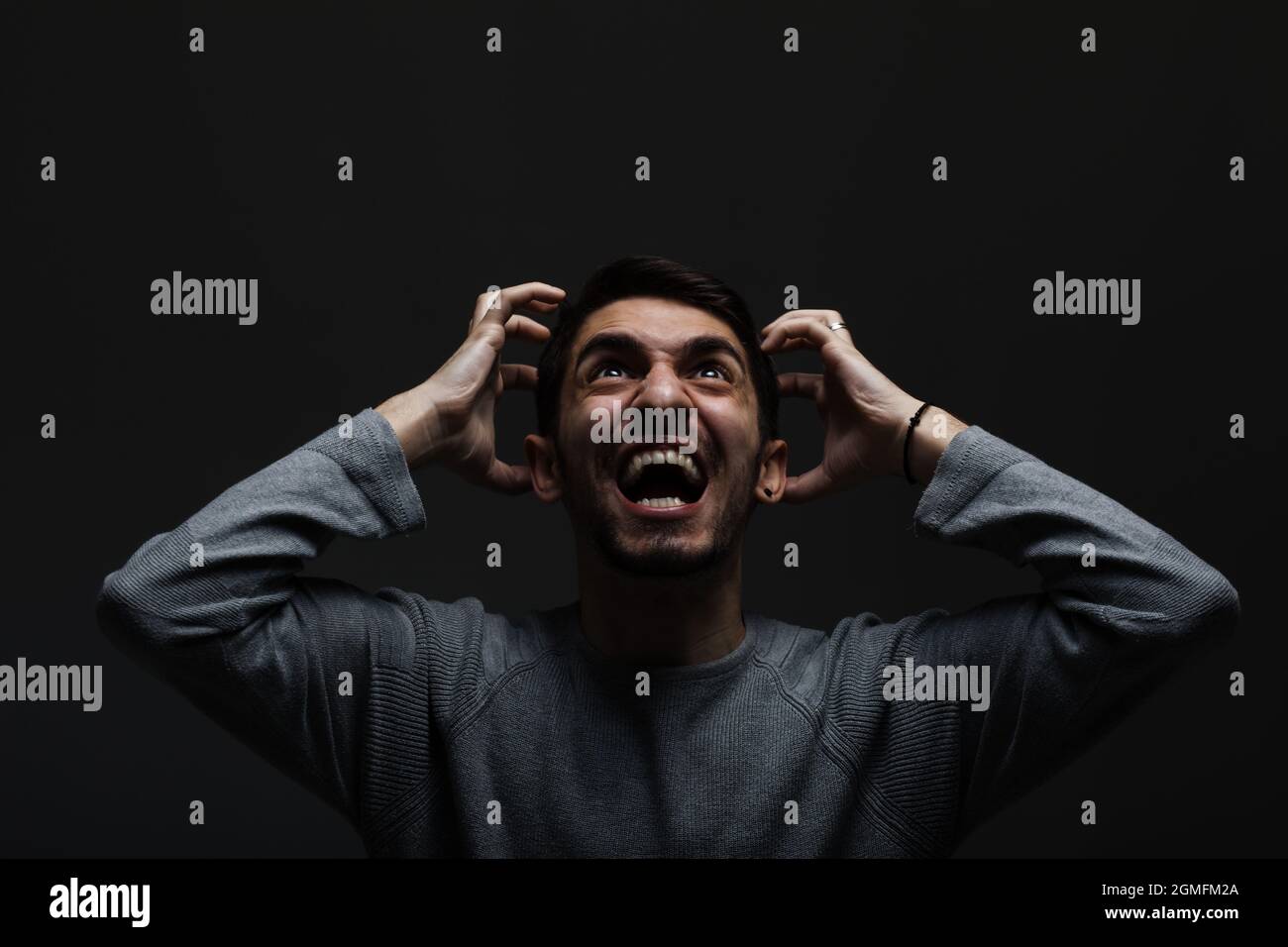 Portrait of young man screaming. Looking up in anger and making angry ...