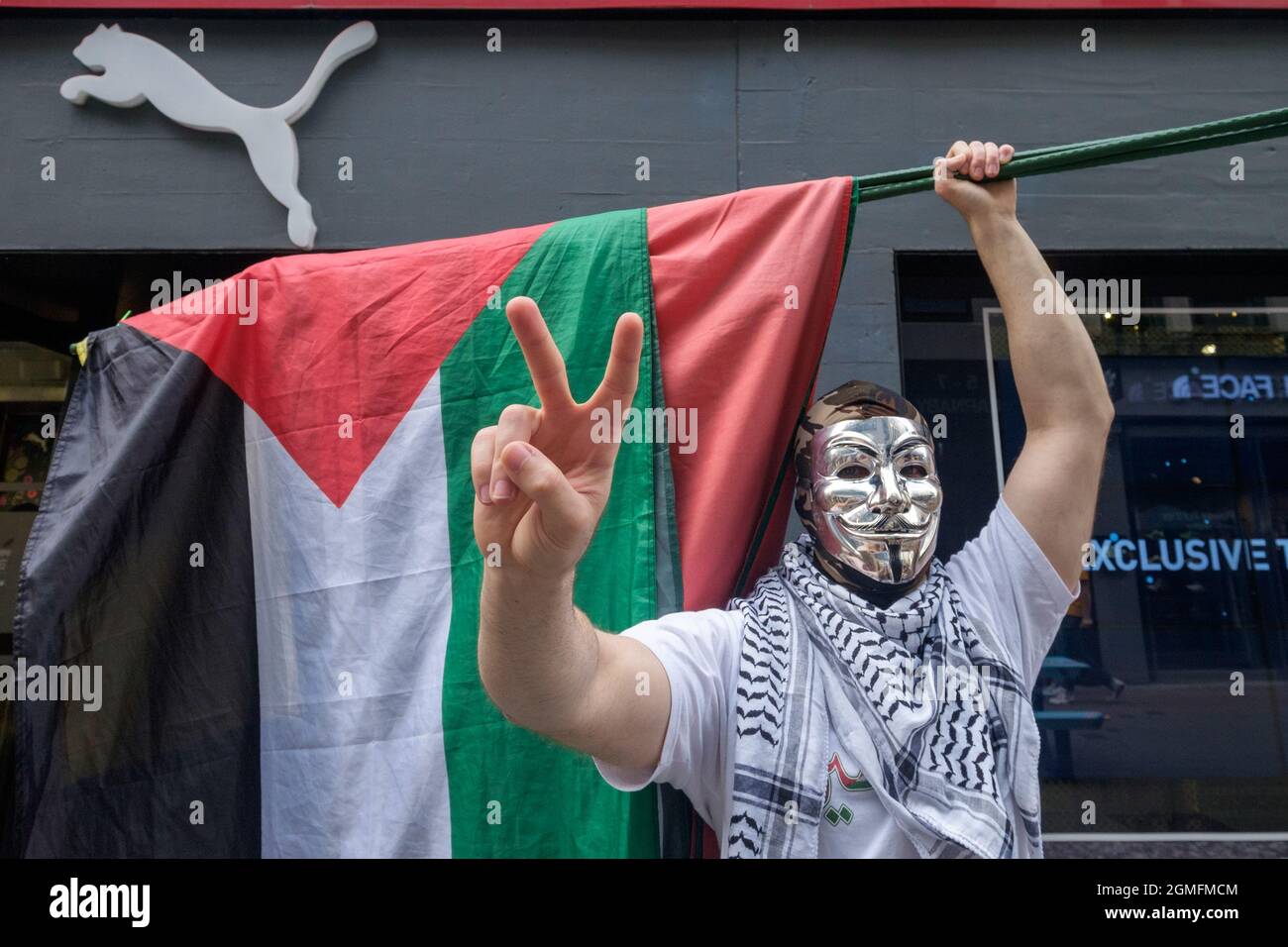 London, UK. 18 Sept 2021. A masked protester poses outside the store ...