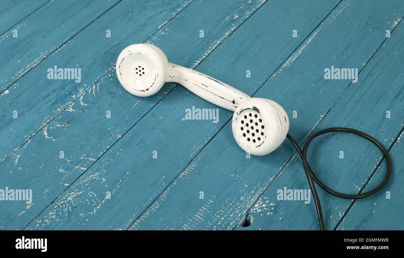 White handset vintage phone on a retro old blue wood textured plank ...