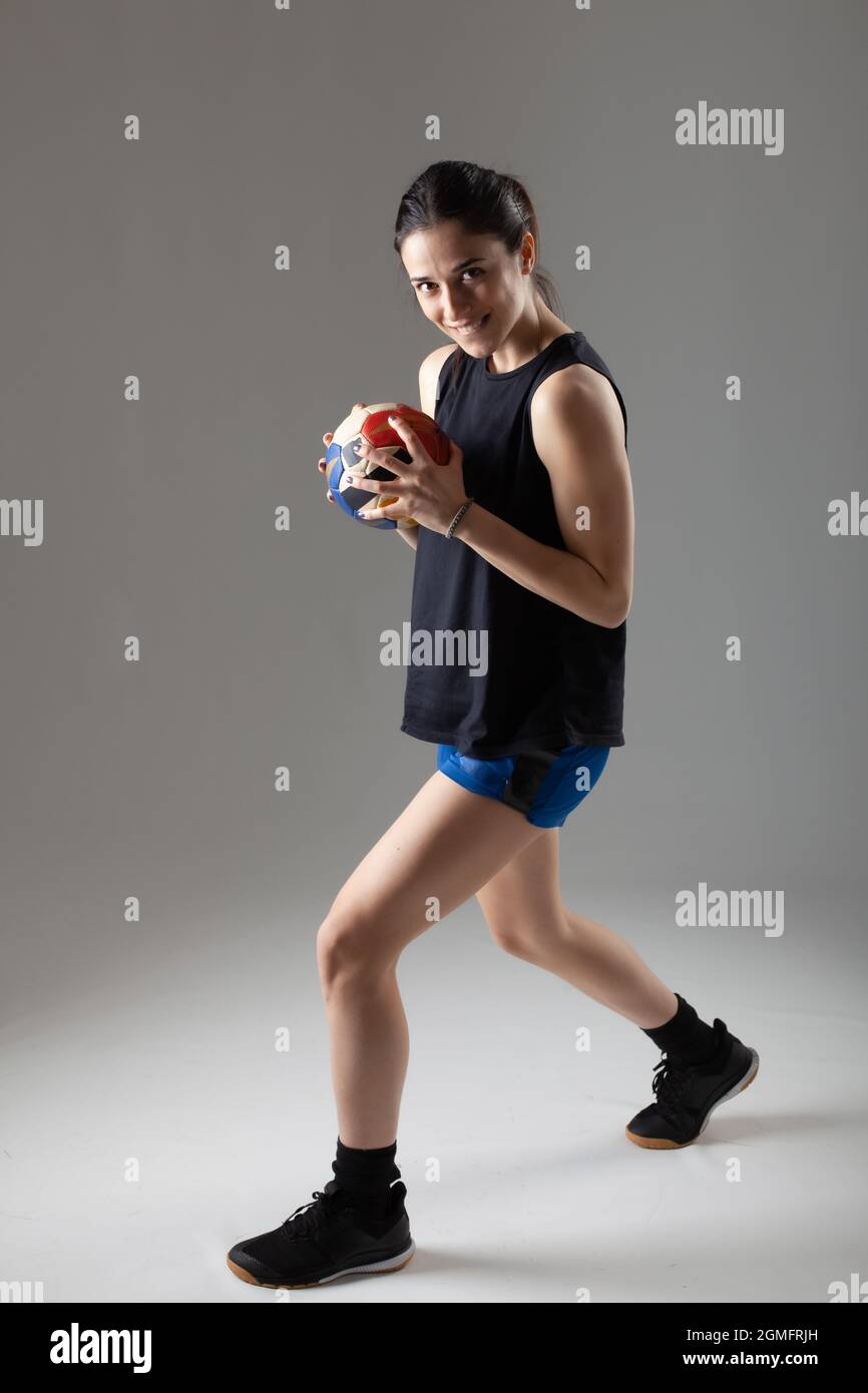 Handball player posing on light gray background. Girl posing with ball ...