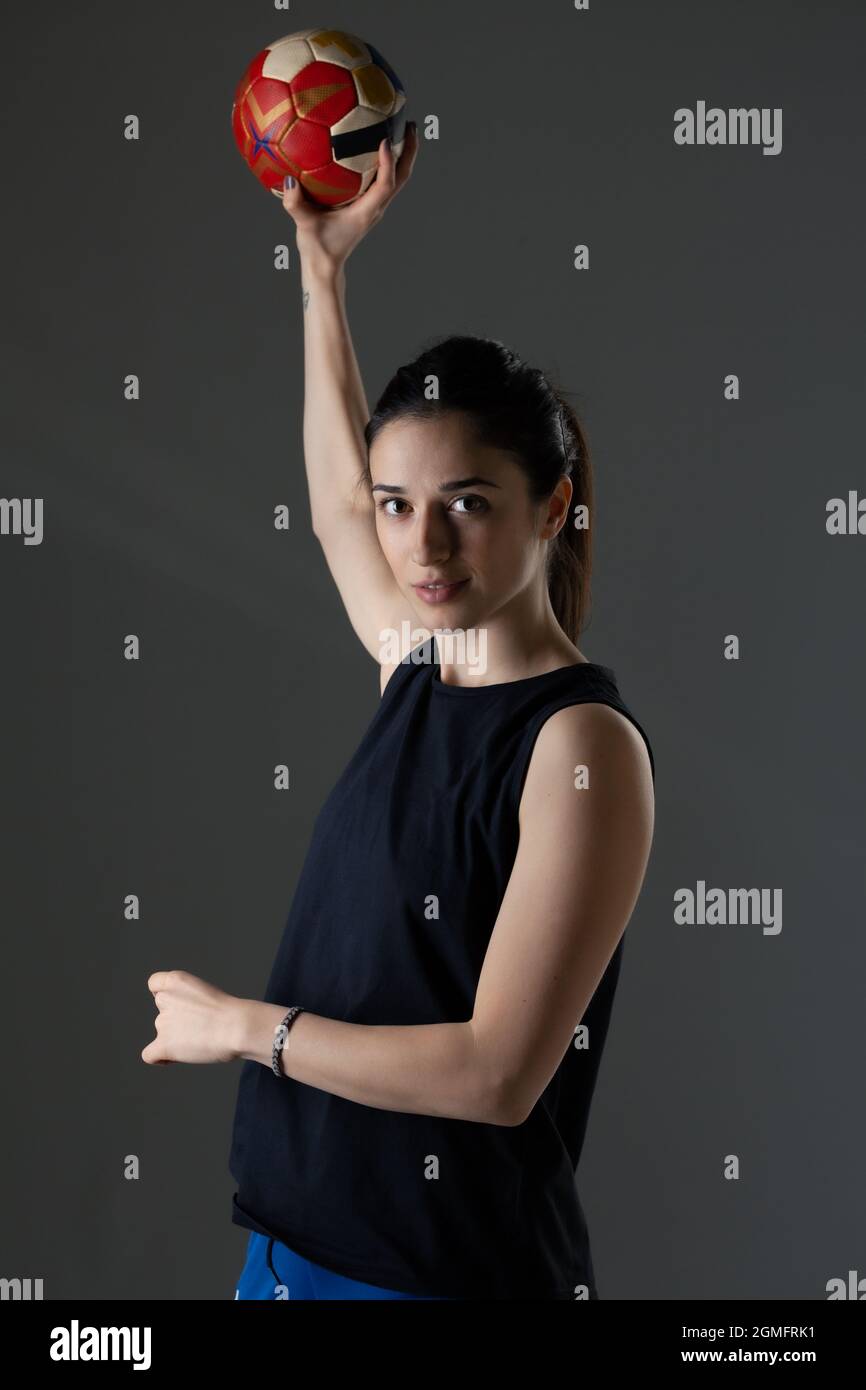 Handball player posing on dark gray background. Girl posing with ball ...