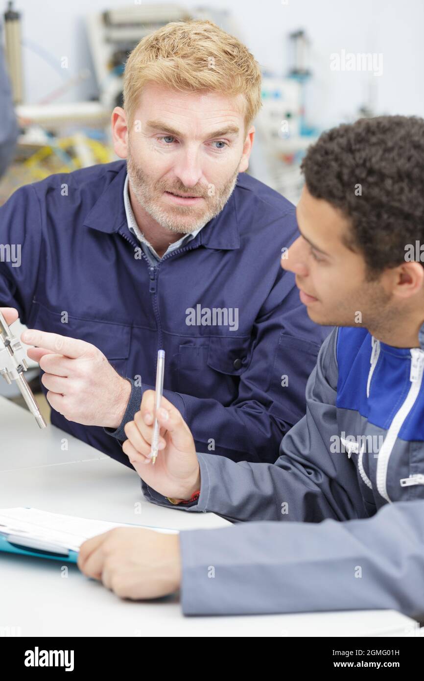 two men measuring detail and assembling product in carpentry workshop ...