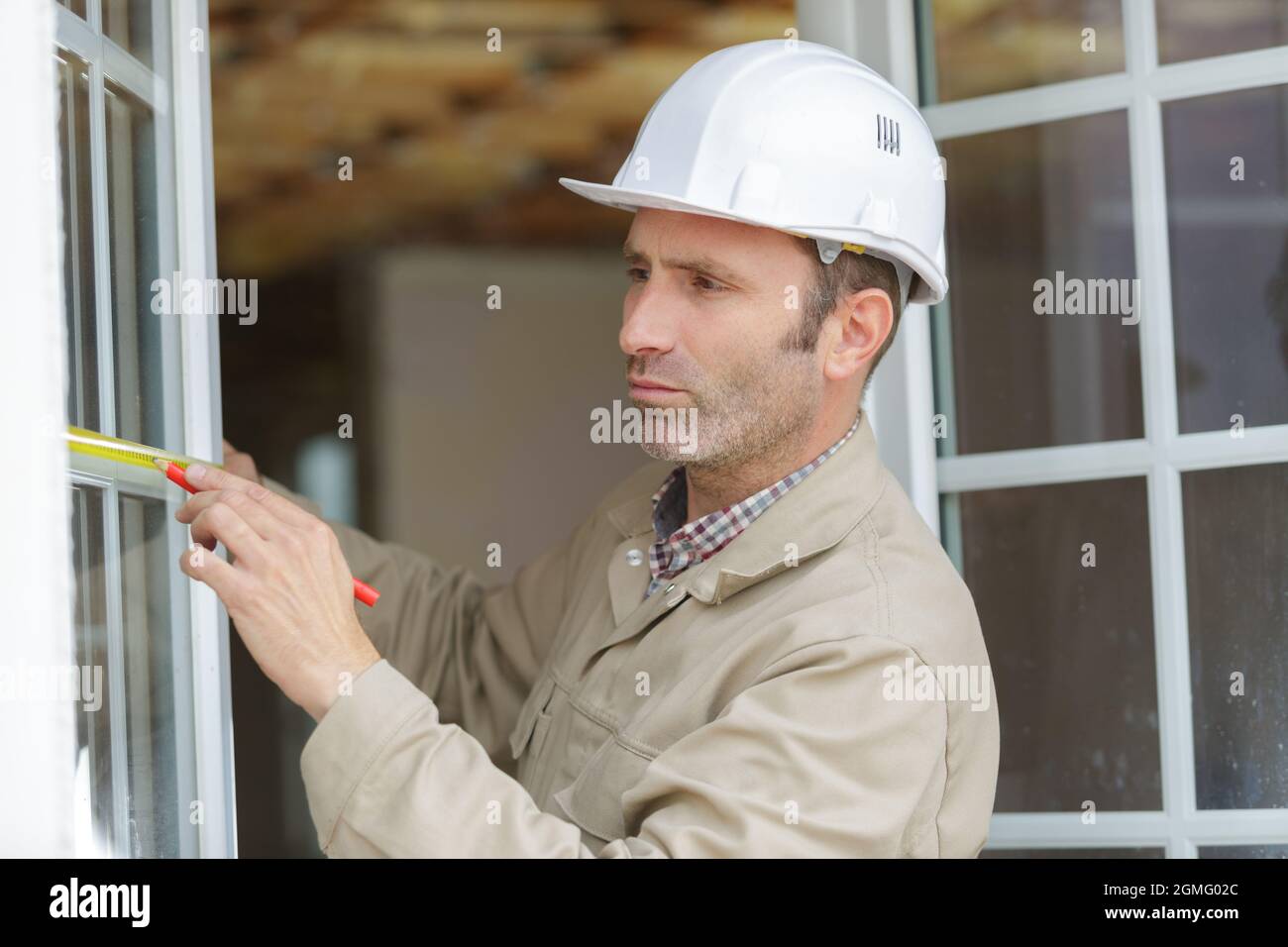 man measuring window prior to installation of roller shutter outdoors ...