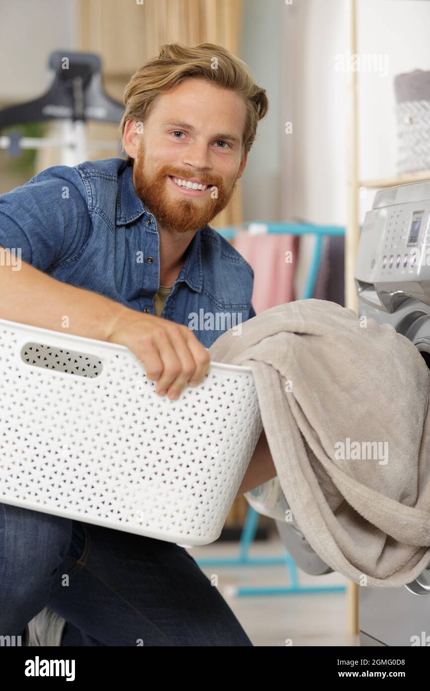 young man loading clothes into washing machine Stock Photo - Alamy