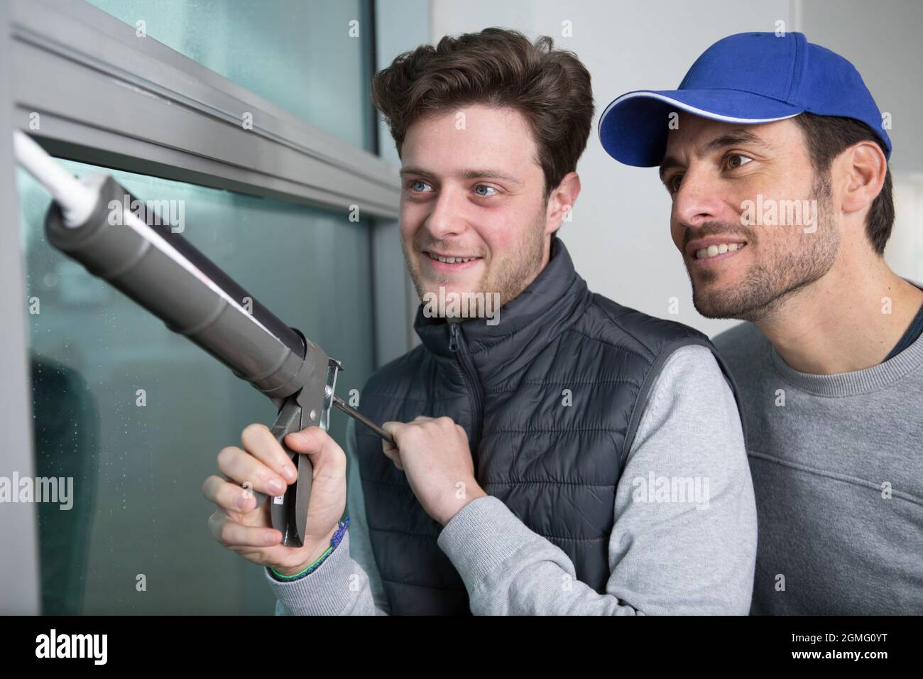 apprentice being advised how to apply caulk to window Stock Photo - Alamy