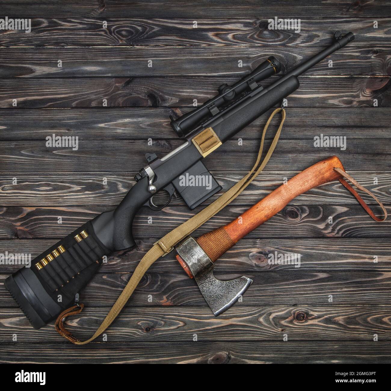 A modern bolt-action rifle with a telescopic sight and an ax with a ...