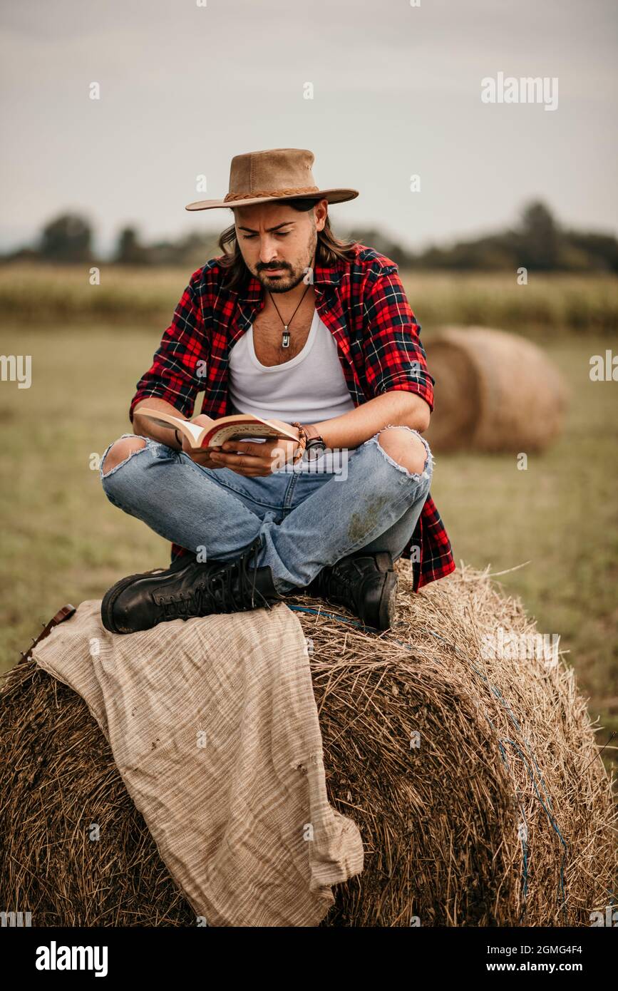 Young handsome Serbian male in a flannel shirt sitting on a haystack ...