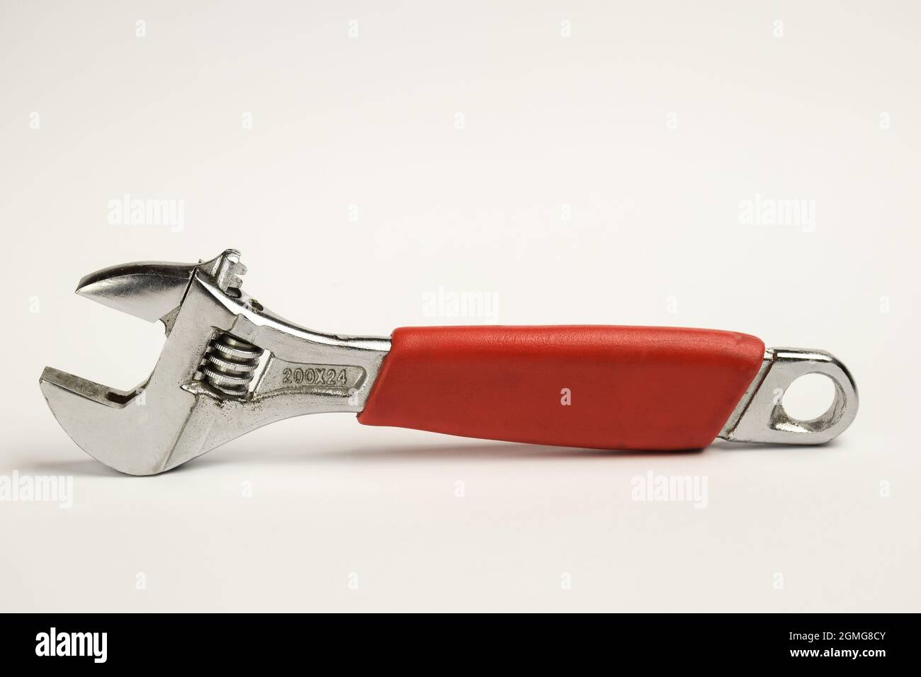 Large adjustable wrench close-up with red handle on white background ...