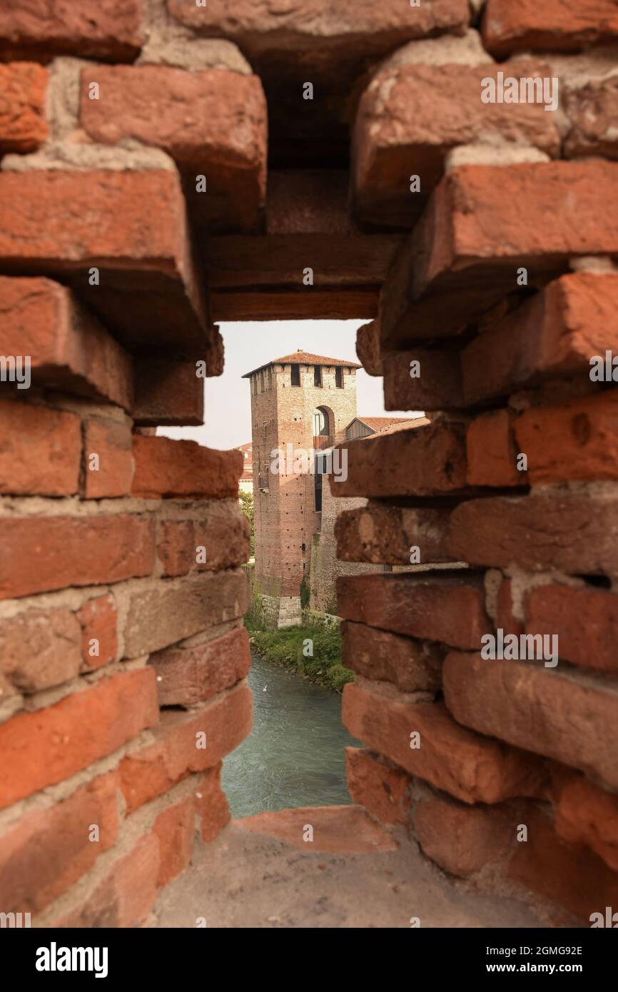 A brick embrasure of a medieval castle, through which the high tower of ...