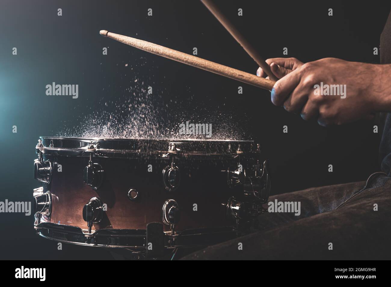 Drummer using drum sticks hitting snare drum with splashing water on ...