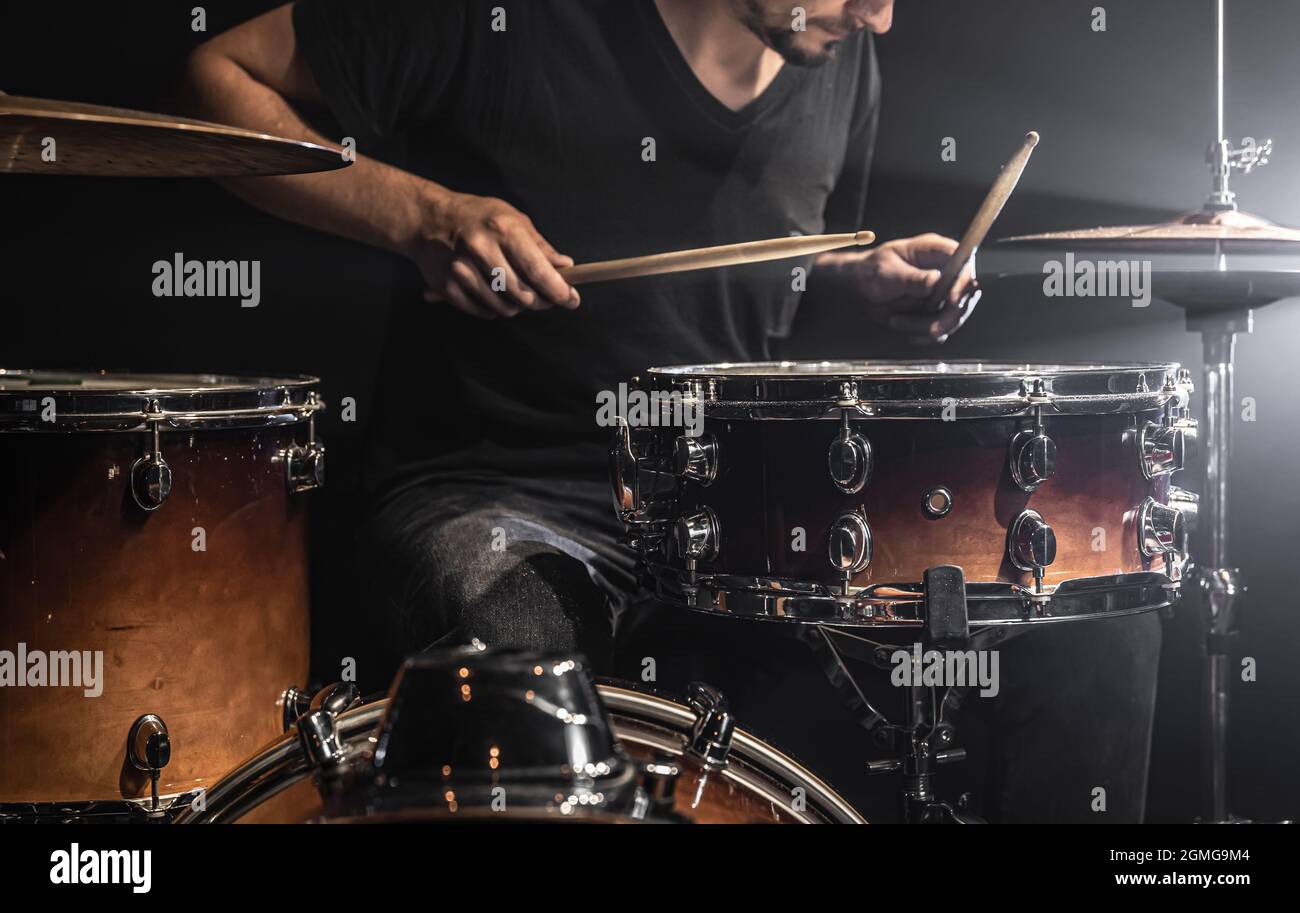 A musician plays drums with sticks on stage with stage lighting Stock ...