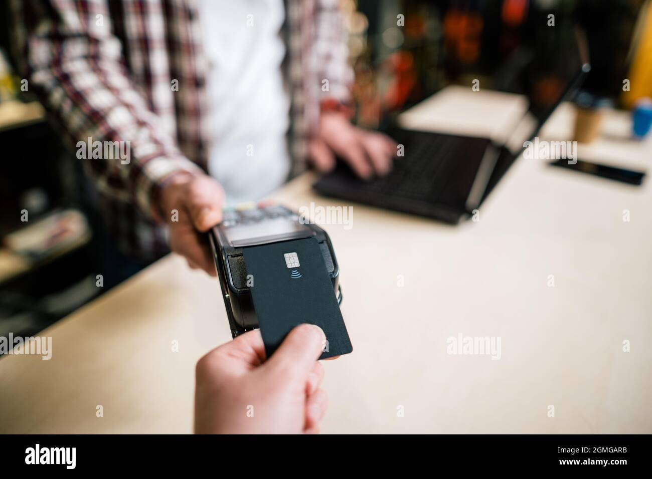 Customer paying by card at store. Seller uses credit card terminal to ...