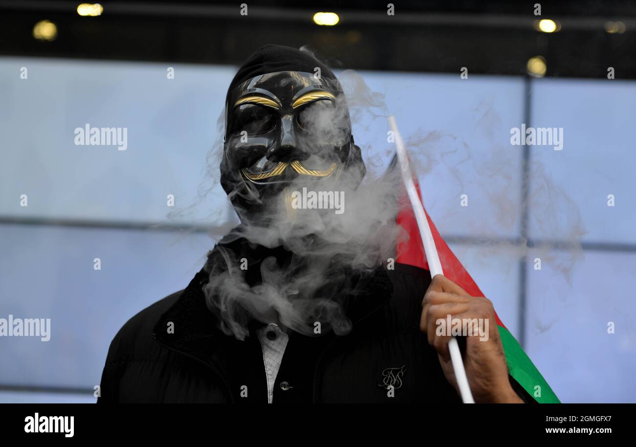 A protestor wearing a Guy Fawkes holding a Palestinian flag, smoking ...