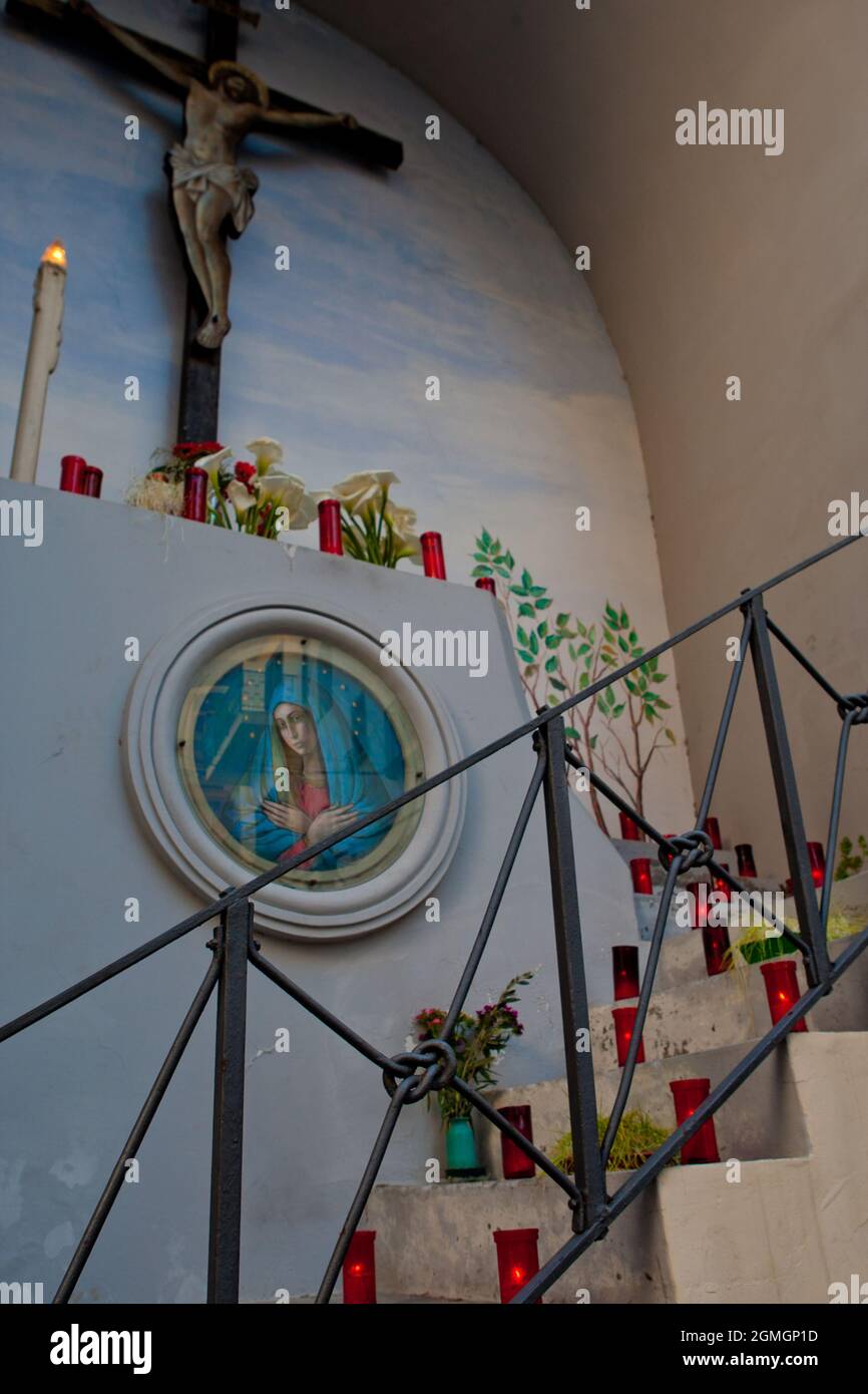 A church altar in Ravello, Italy features candles, a madonna painting ...