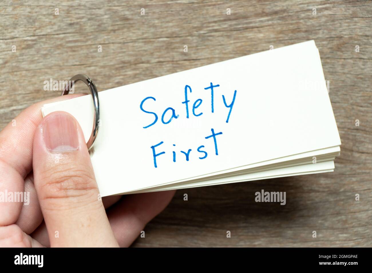 Man hold the flash card with handwriting word safety first on wood ...