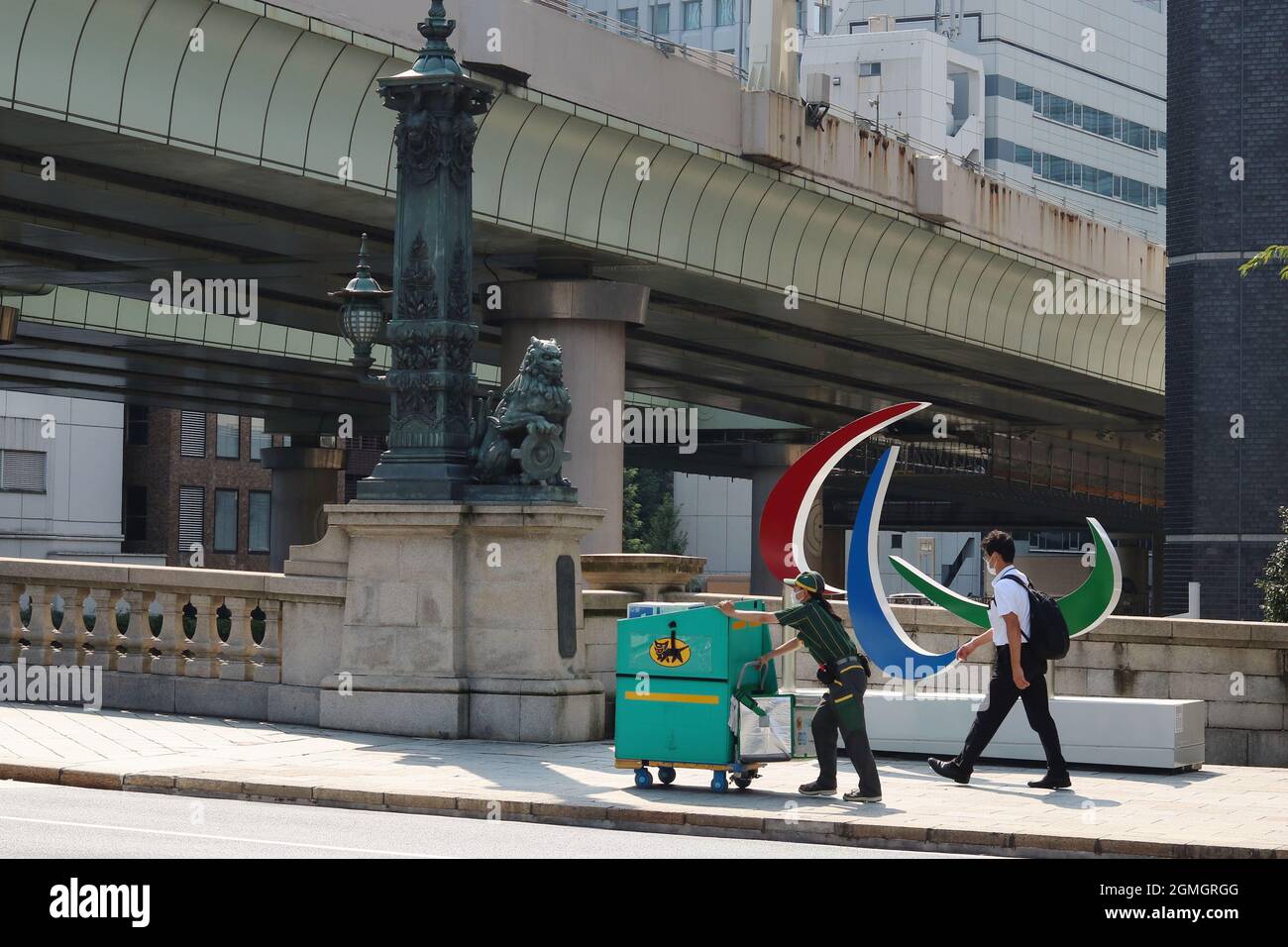 People, including a Yamato delivery worker, pass a Paralympic symbol ...