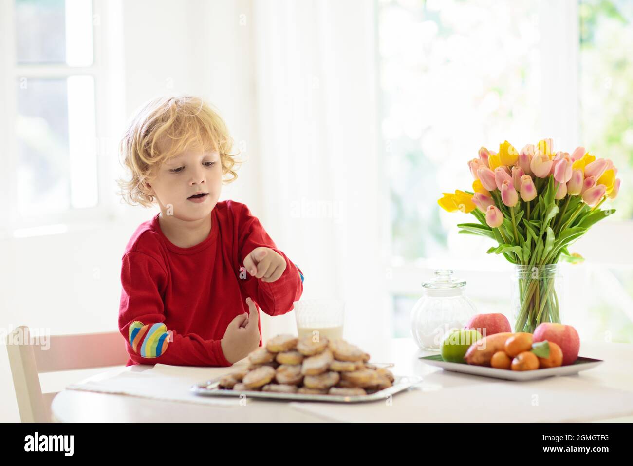 Child eating breakfast. Kid drinking milk with fresh homemade cookies ...