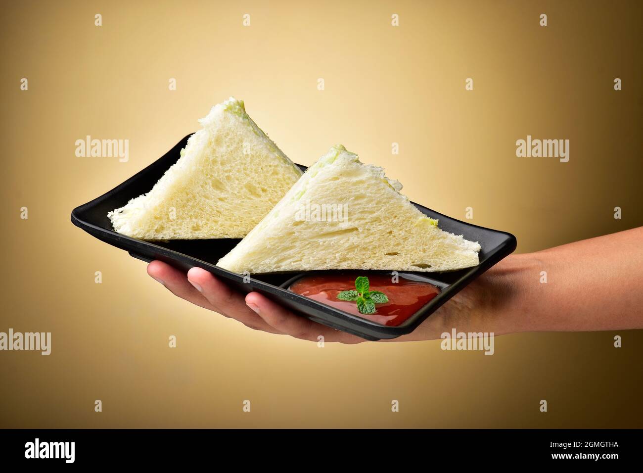 Sandwich with tomato ketchup plate in hand over brown background Stock ...